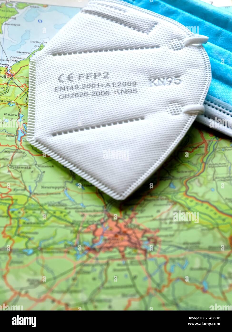 A single medical face mask and a FFP2 mask on a map as a symbol for ...