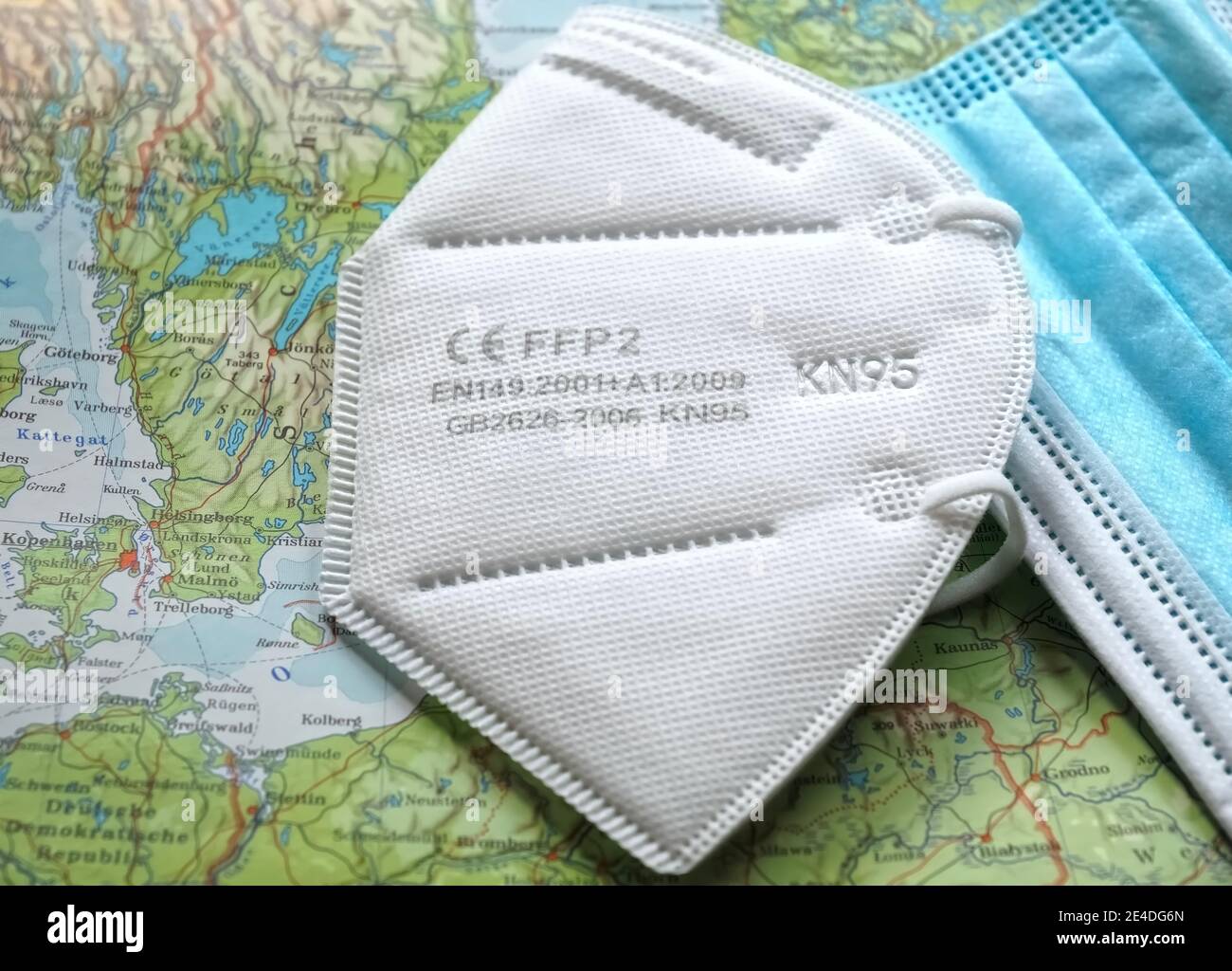 A single medical face mask and a FFP2 mask on a map as a symbol for ...