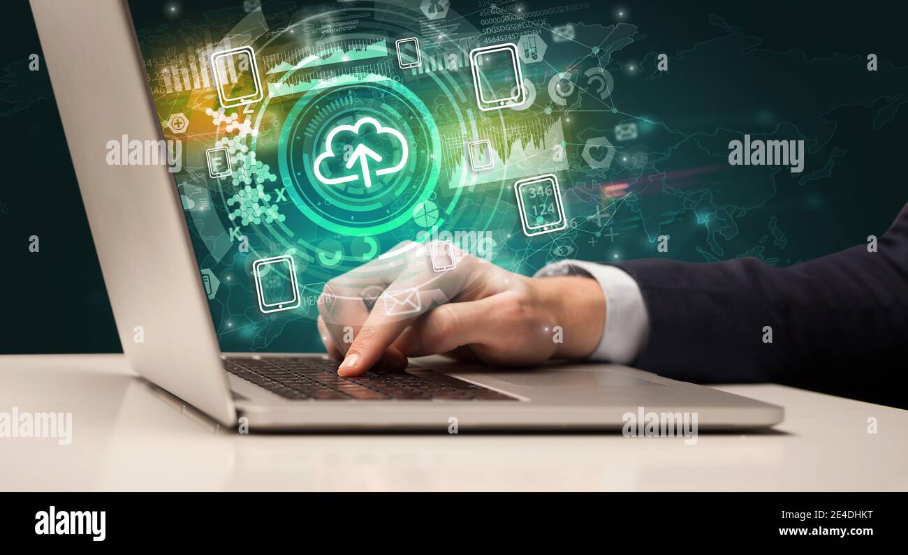 Business hand typing on a modern laptop with upload to cloud icon ...