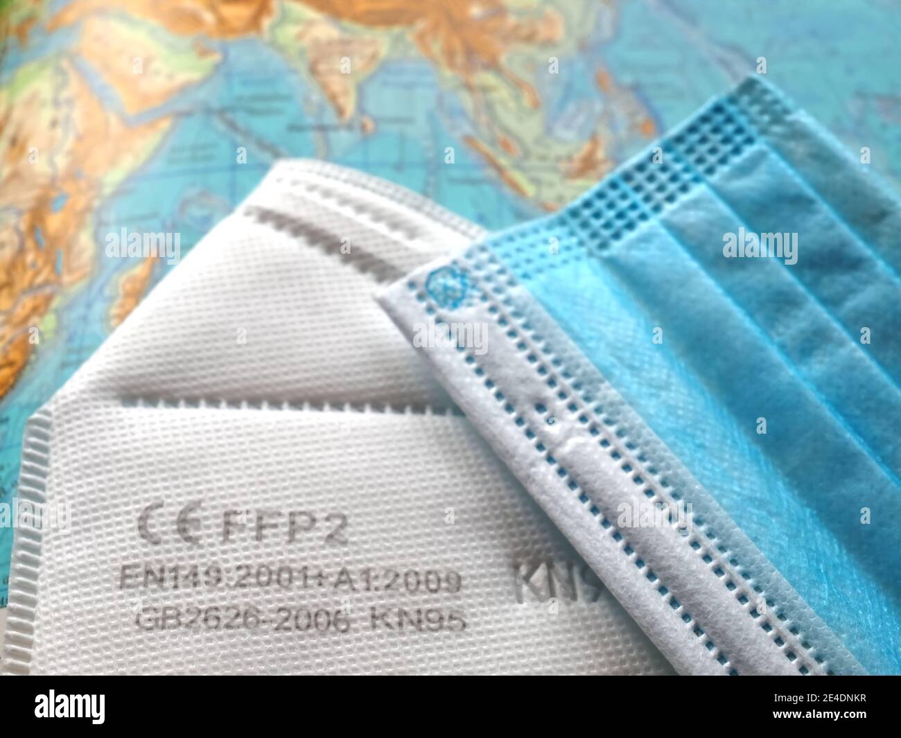 A single medical face mask and a FFP2 mask on a map as a symbol for ...