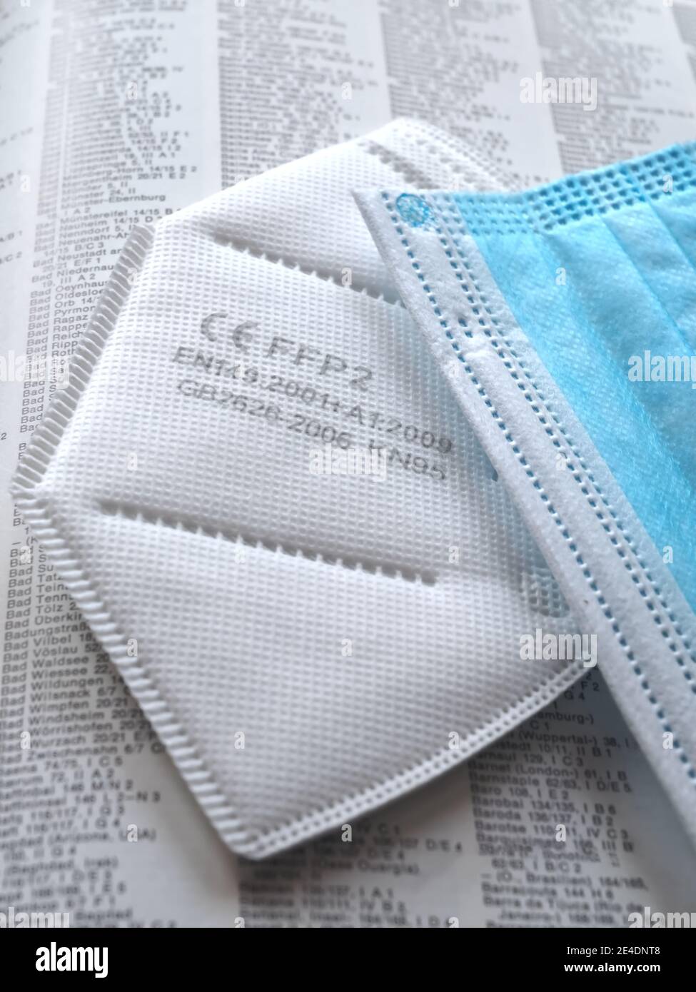 A single medical face mask and a FFP2 mask on city names as a symbol ...