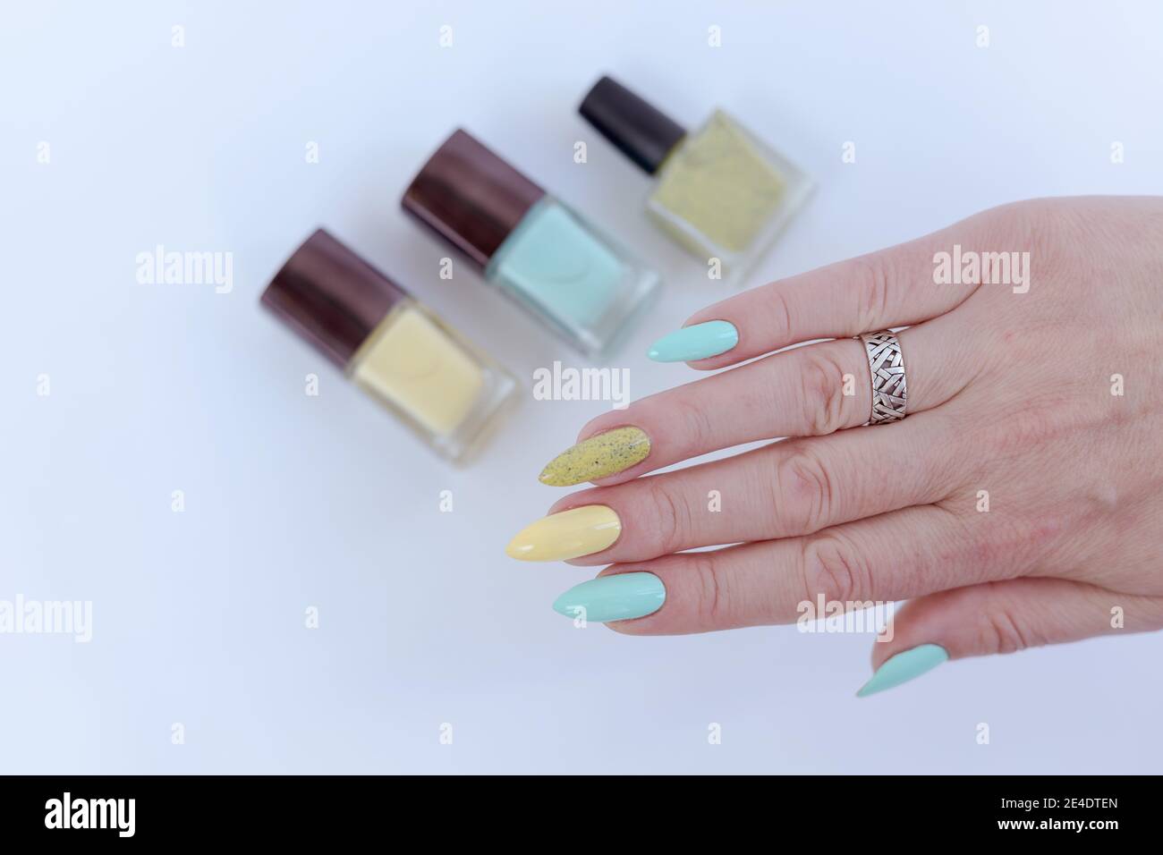 Female hand with long nails and multi-colored manicure, bottles of nail ...