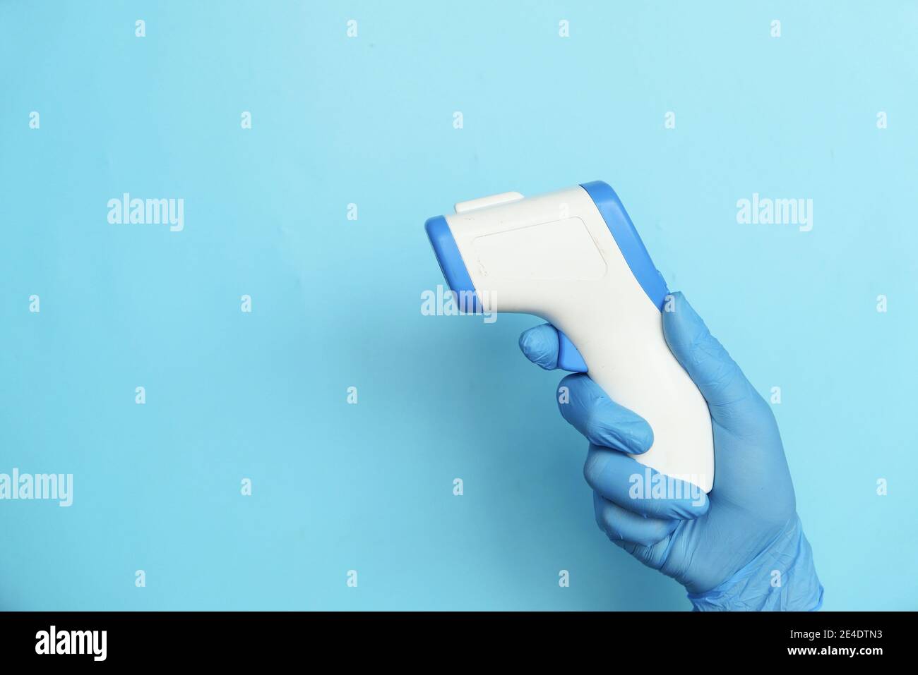 Hand holding infrared thermometer to measuring temperature on blue ...