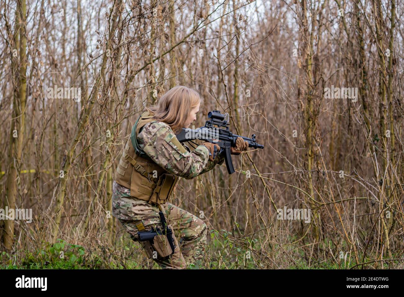 Beautiful girl in military uniform with an airsoft gun in the forest ...