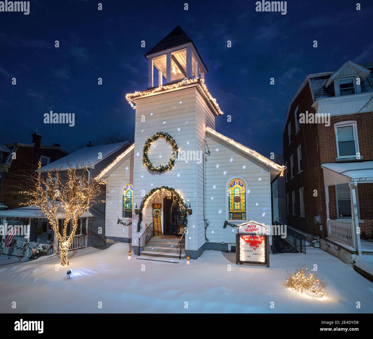Small white church decorated with Christmas lights with snow at night ...
