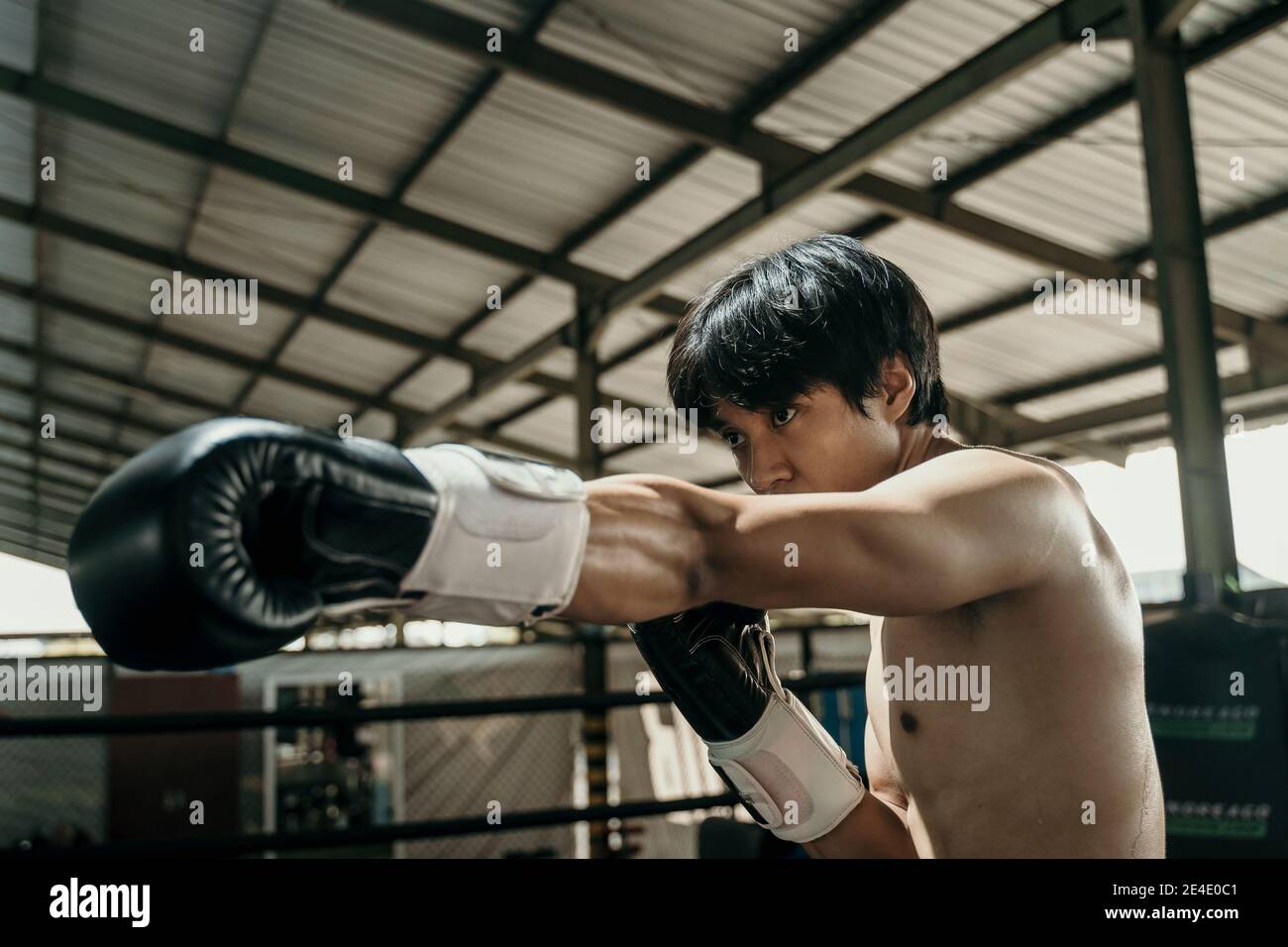 shot from side of boxer over boxing ring background make a punch motion ...