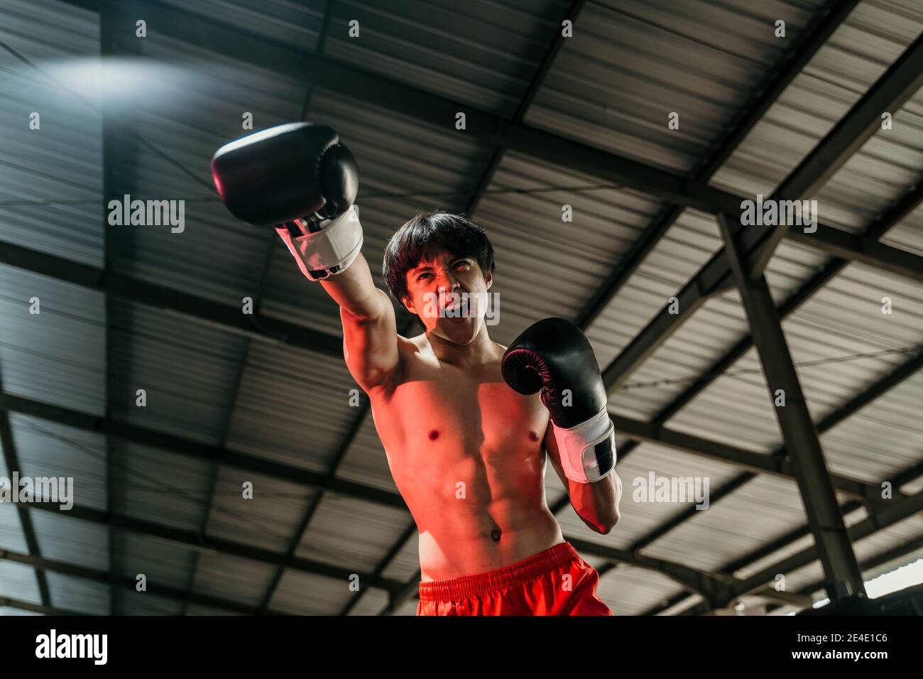 Young man looking aggressive with boxing gloves make a punch motion on ...