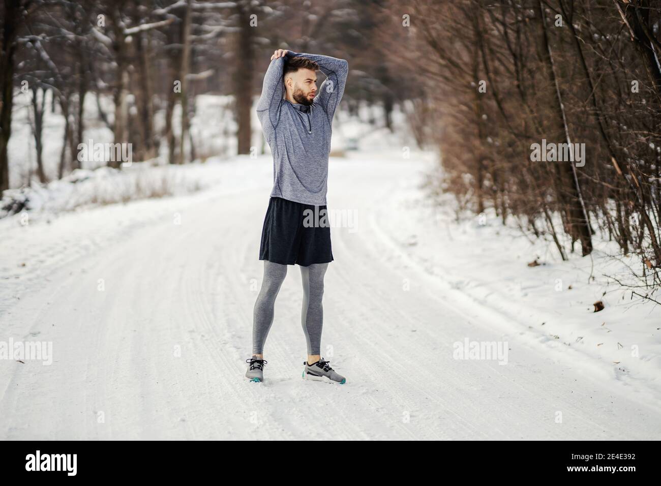 Fit sportsman doing stretching and warm up exercises while standing on ...