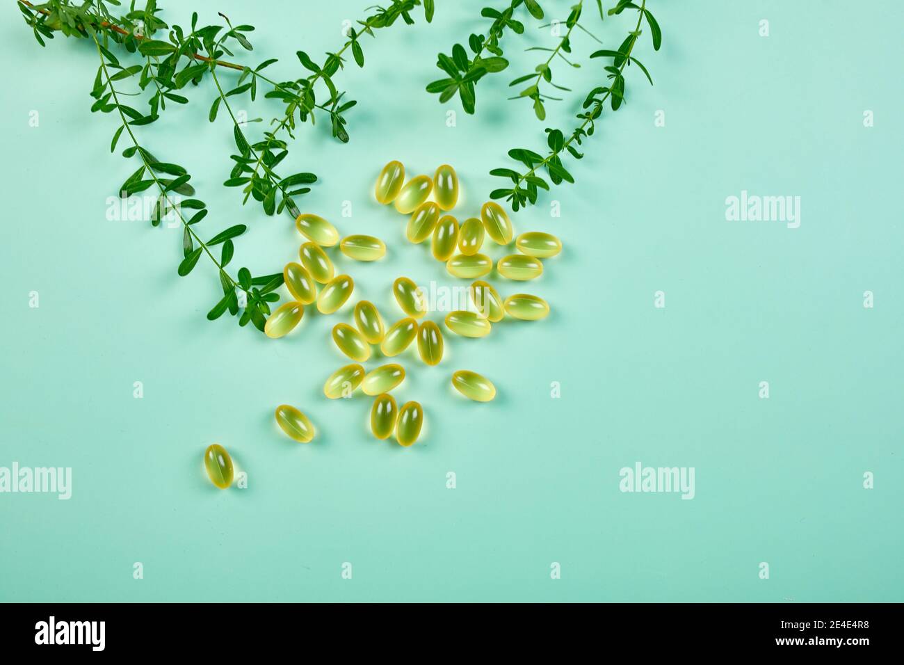 Capsules with fish oil and green leaves on green background, Healthcare ...