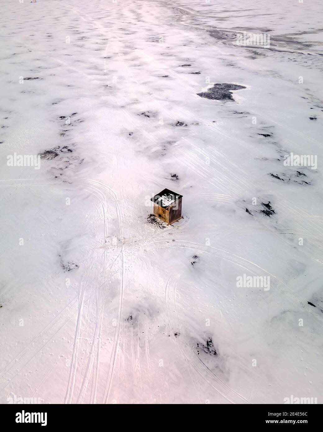 Aerial view of a wooden small hut in the middle of a frozen snow ...