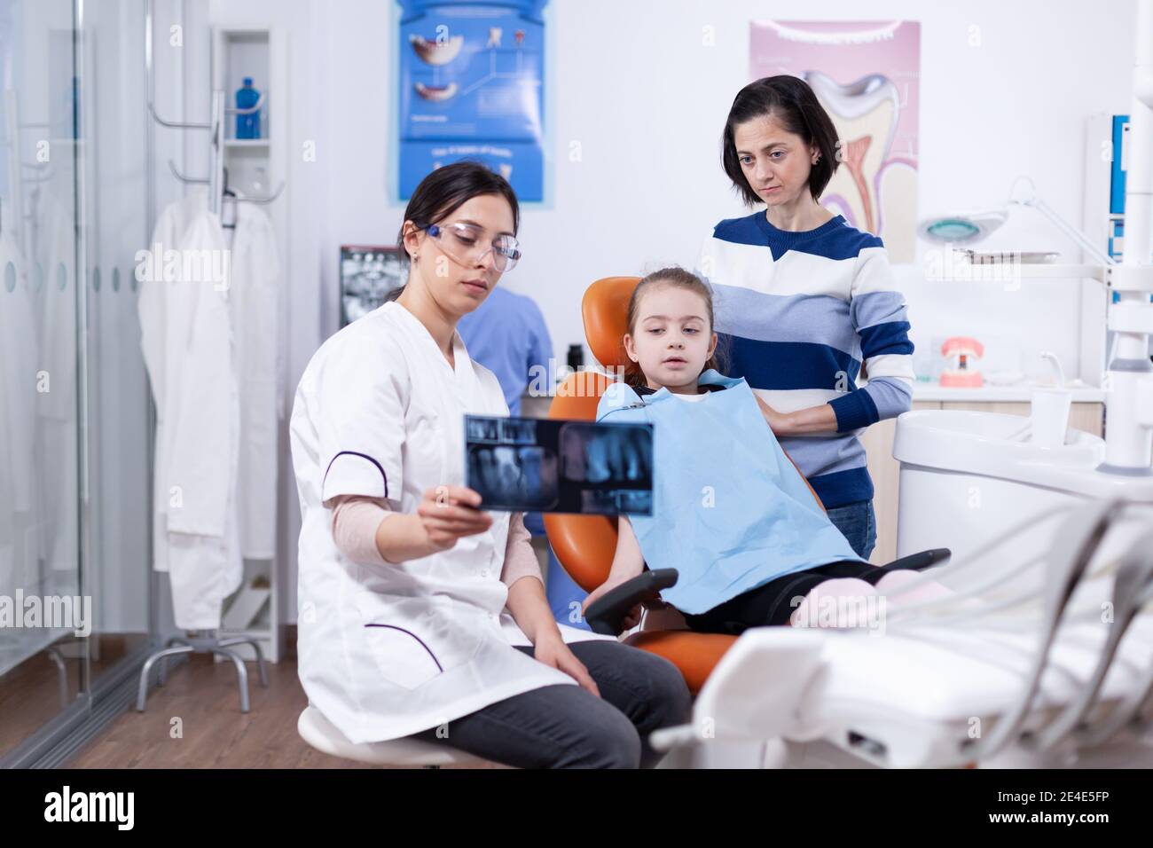 Little girl and parent listening dentist advice pointing at dental ...
