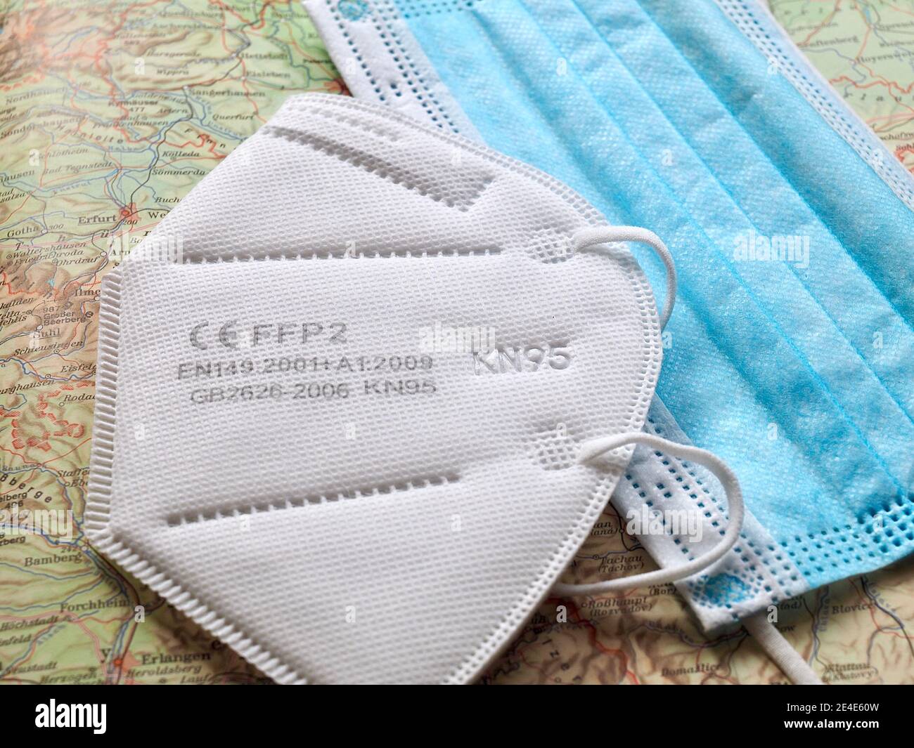 A single medical face mask and a FFP2 mask on a map as a symbol for ...