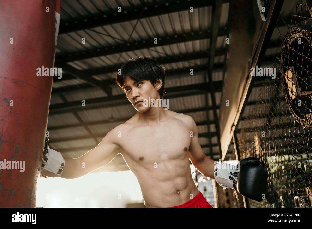 asian man boxer during boxing hiting heavy bag at training fitness gym ...