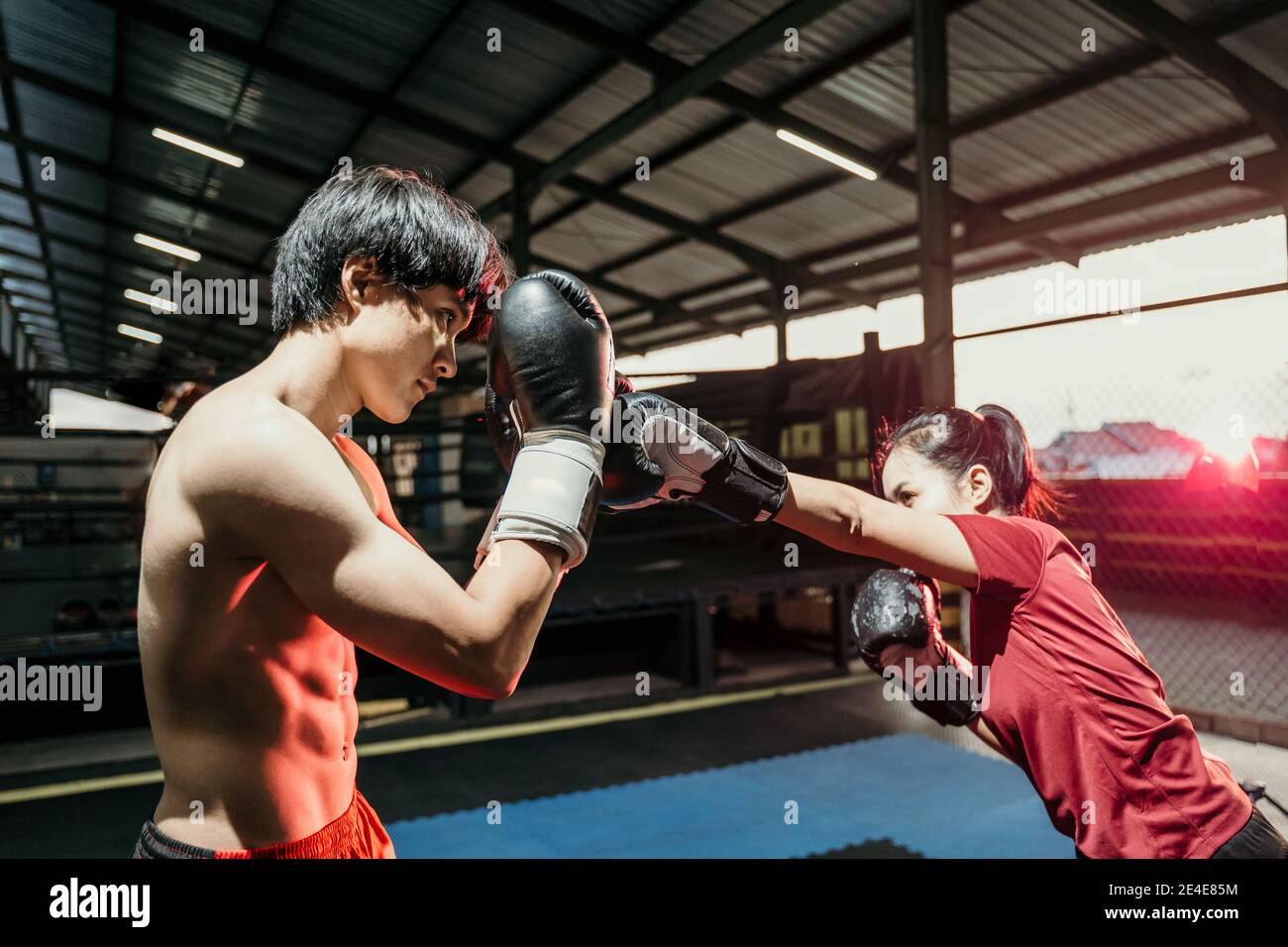 Female fighter attacking with punch motion and male boxer doing defend ...