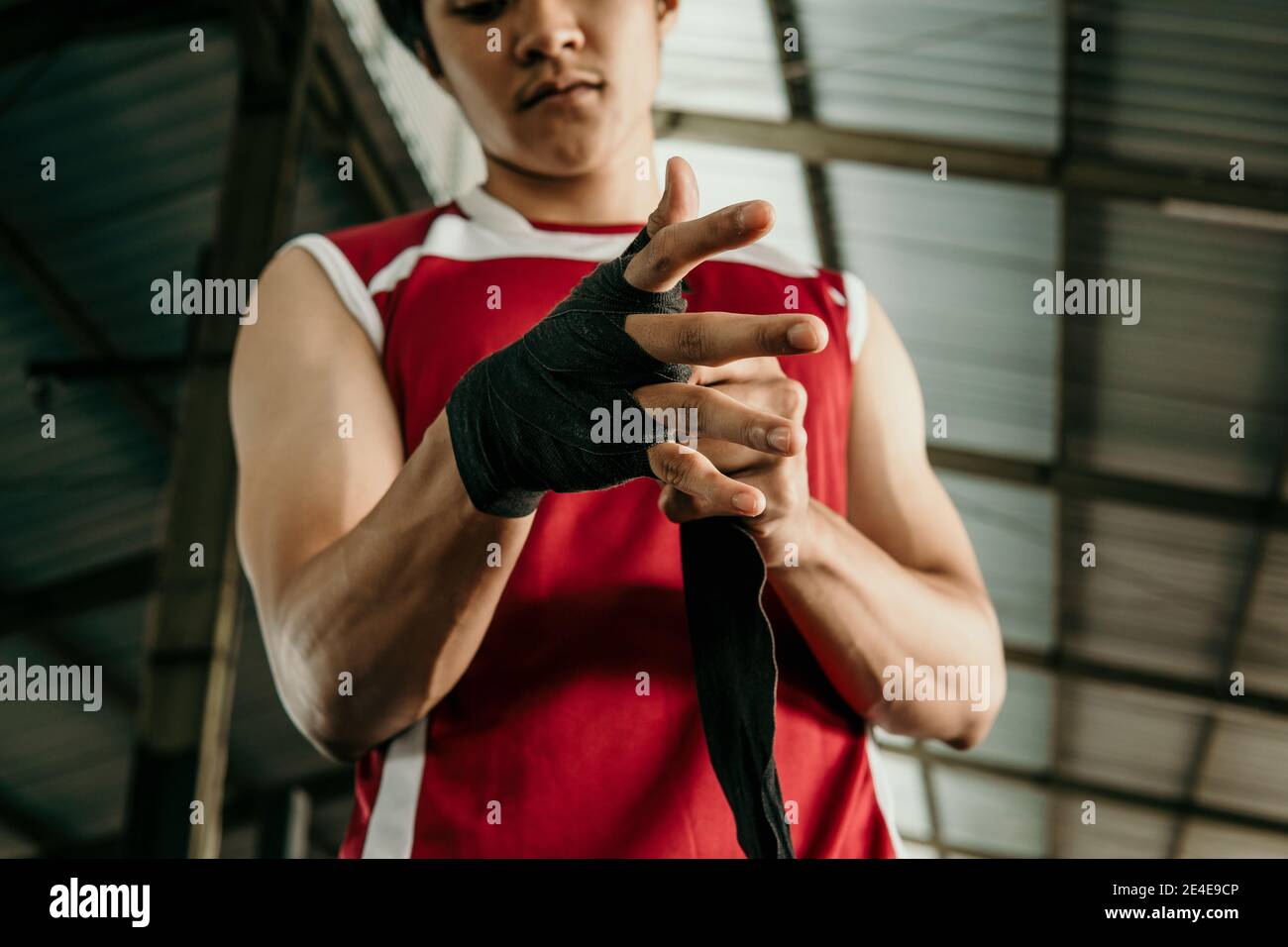 portrait of boxer fighter applying bondage tape on hands over fighting ...