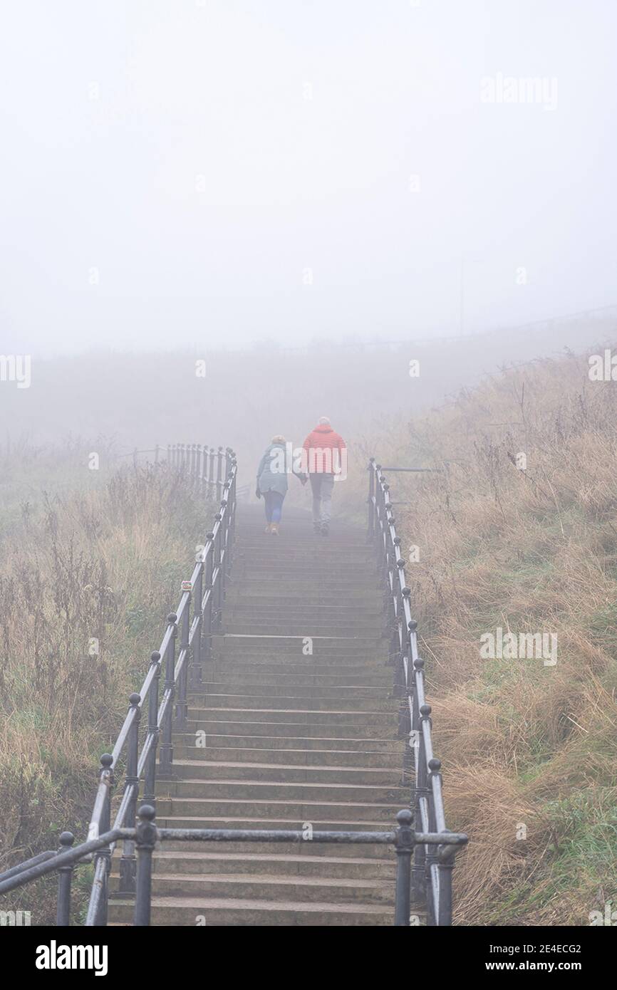 two people walking away up steps in mist Stock Photo - Alamy