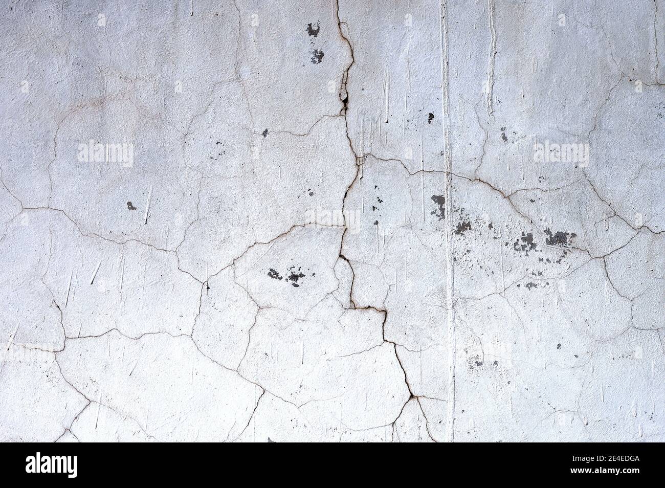 detail of a white wall cracked and deteriorated by the passage of time ...
