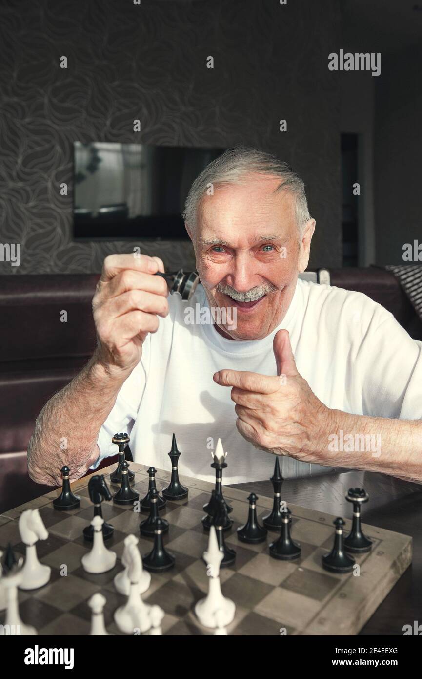 Portrait of a happy elderly man playing chess. man rejoices in victory ...