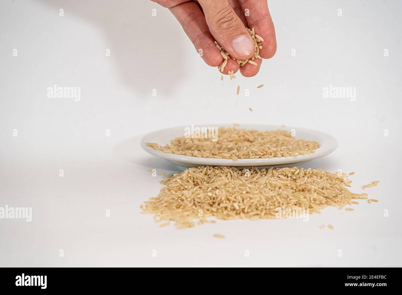 Hand pouring out rice onto a heap isolated on a white surface Stock ...