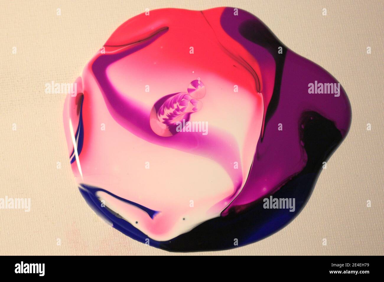 A close up photograph of a pink and purple paint splodge on canvas ...