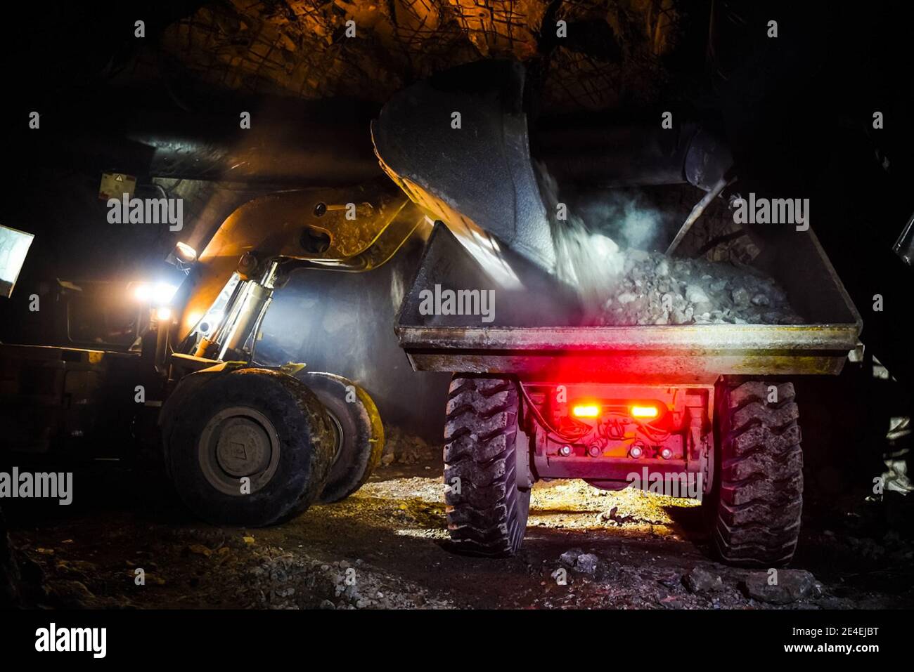 Loading the rock with a bulldozer into a dump truck. Work in the mine ...