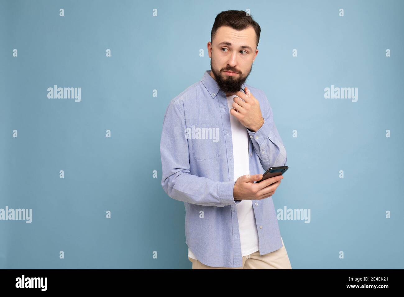 Thoughtful handsome young man isolated over background wall wearing ...