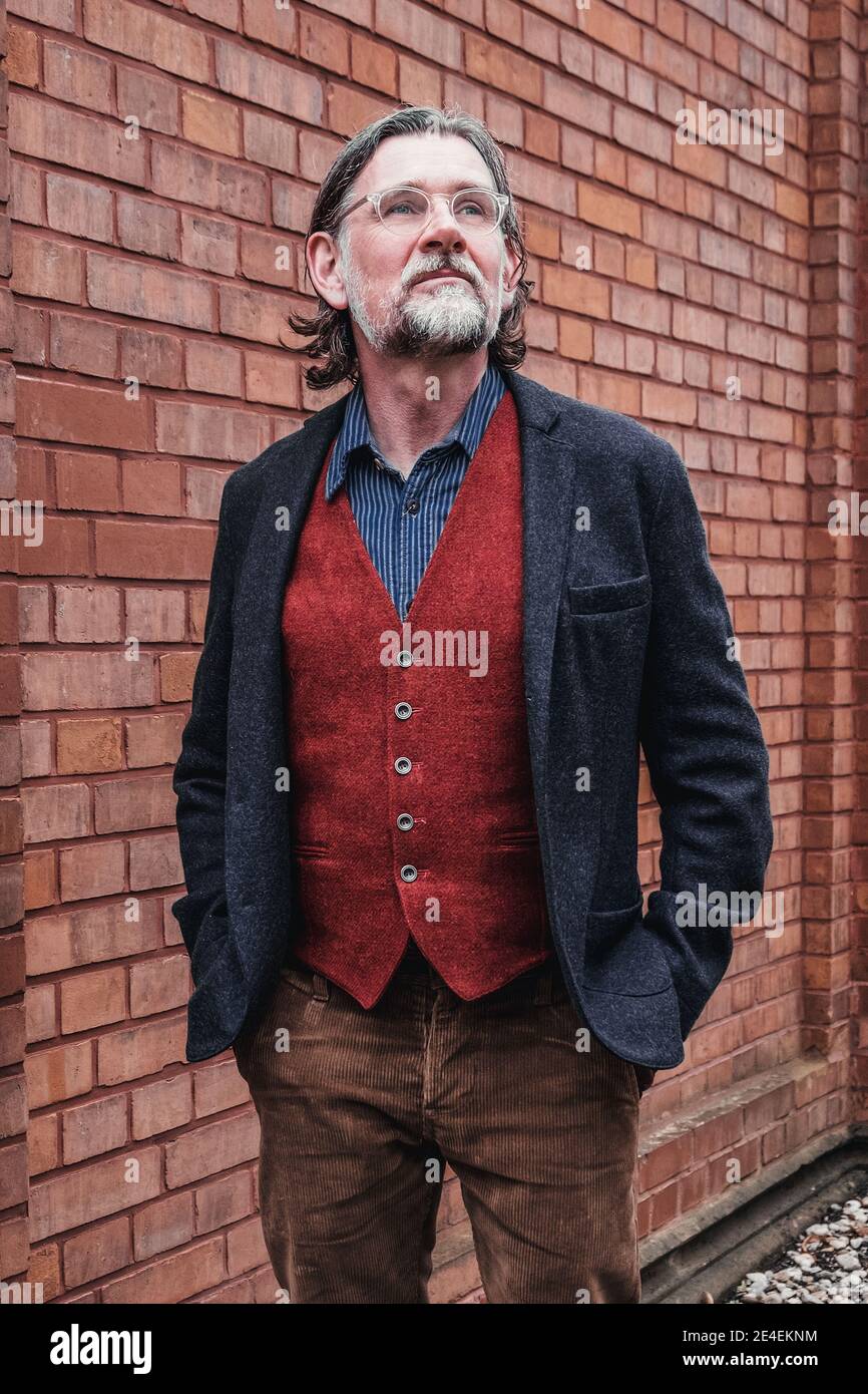 handsome man in his 50s standing in front of brickwall Stock Photo - Alamy