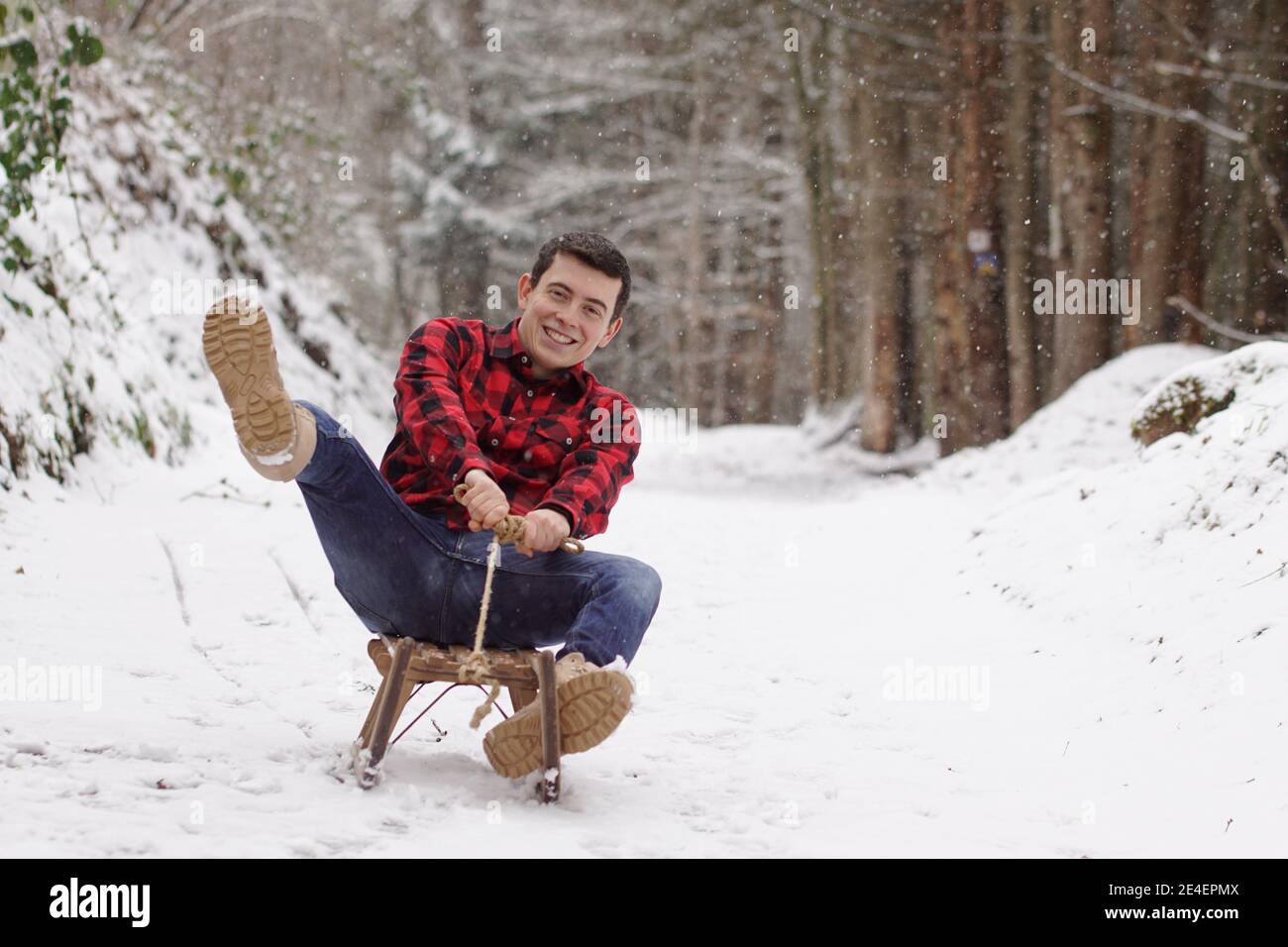 Back to childhood - Happy man riding a sledge, having fun and laughing ...