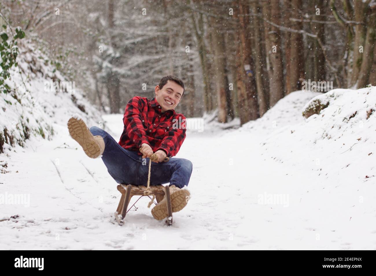 Back to childhood - Happy man riding a sledge, having fun and laughing ...
