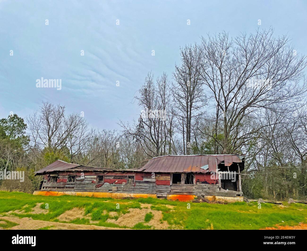 Old damaged and fallen apart structure and green grass in a rural ...