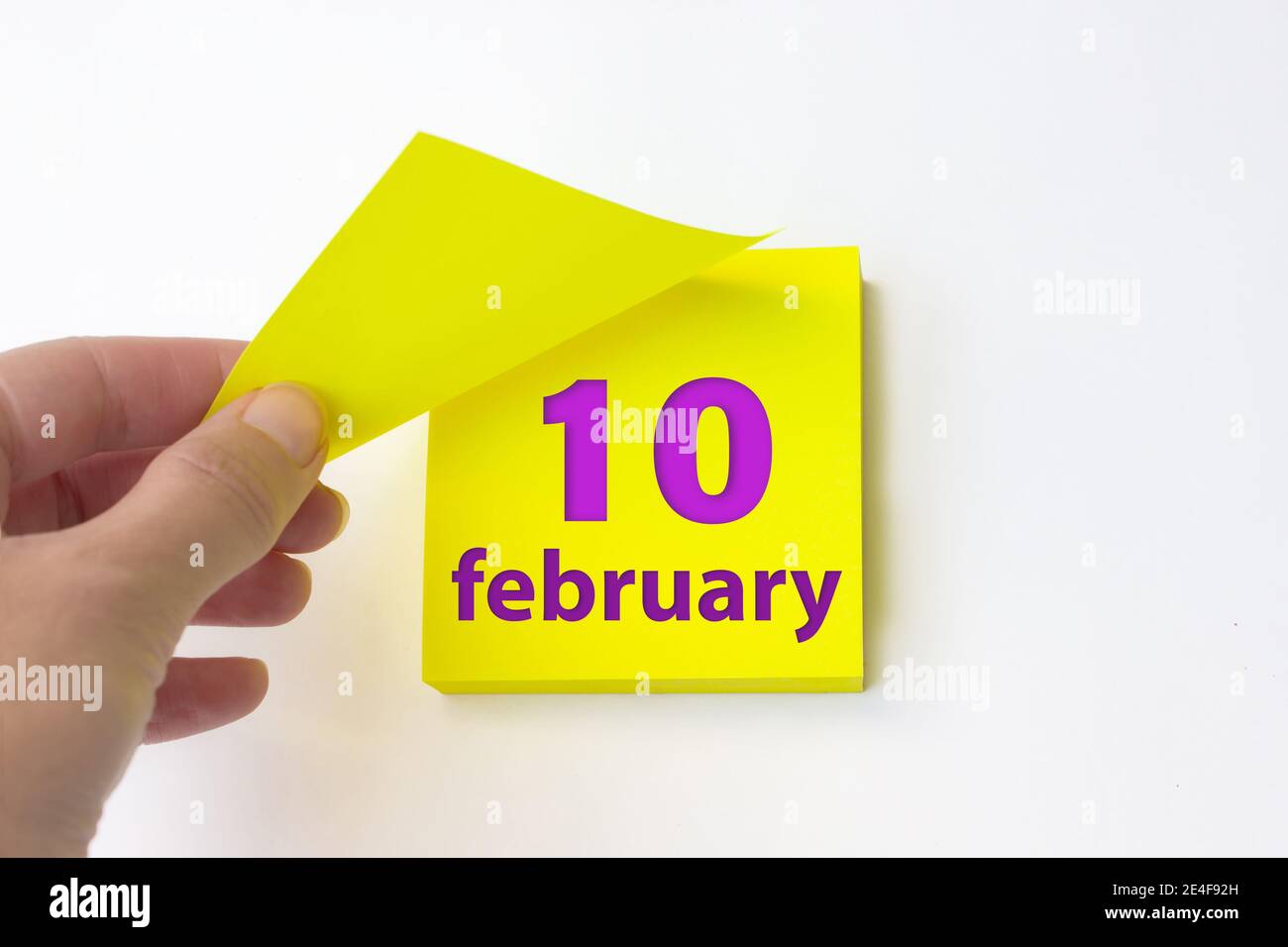 February 10th. Day 10 of month, Calendar date. Hand rips off the yellow ...