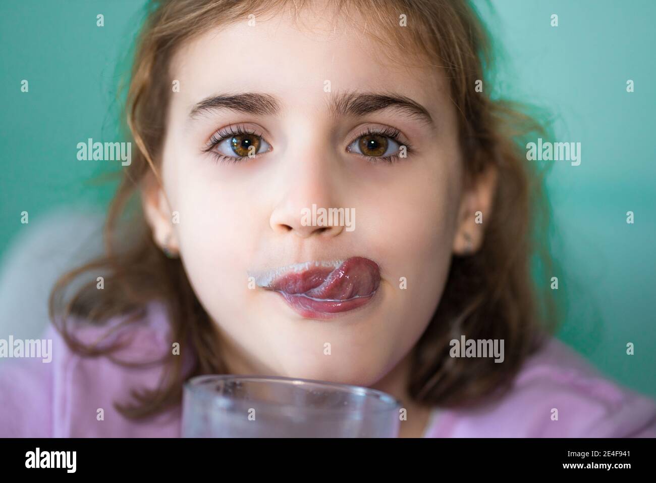 girl tastes milk glass and licks her lips, healthy eating concept ...