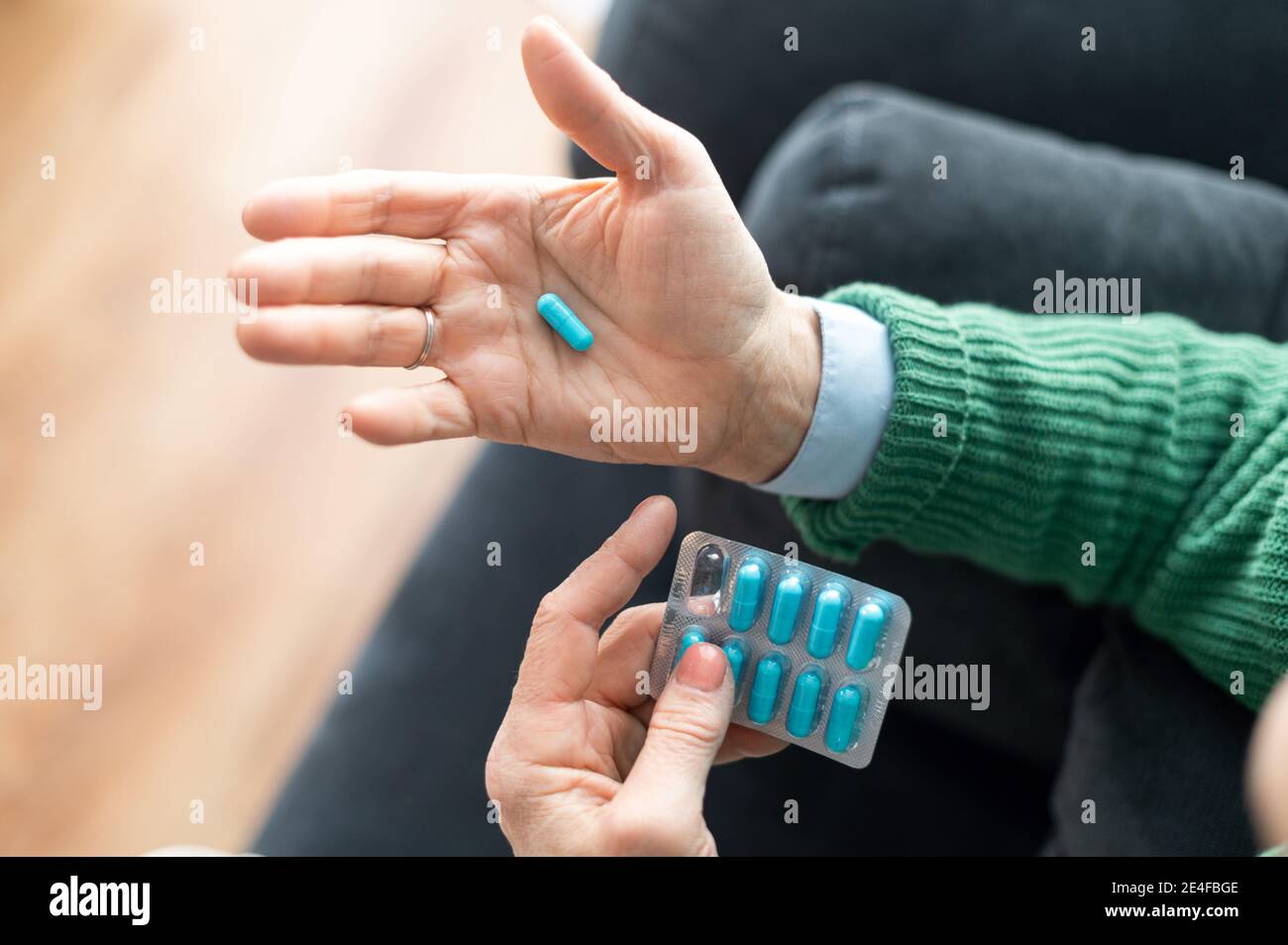 Top view of female hand holding a blue prescription pill and a blister ...
