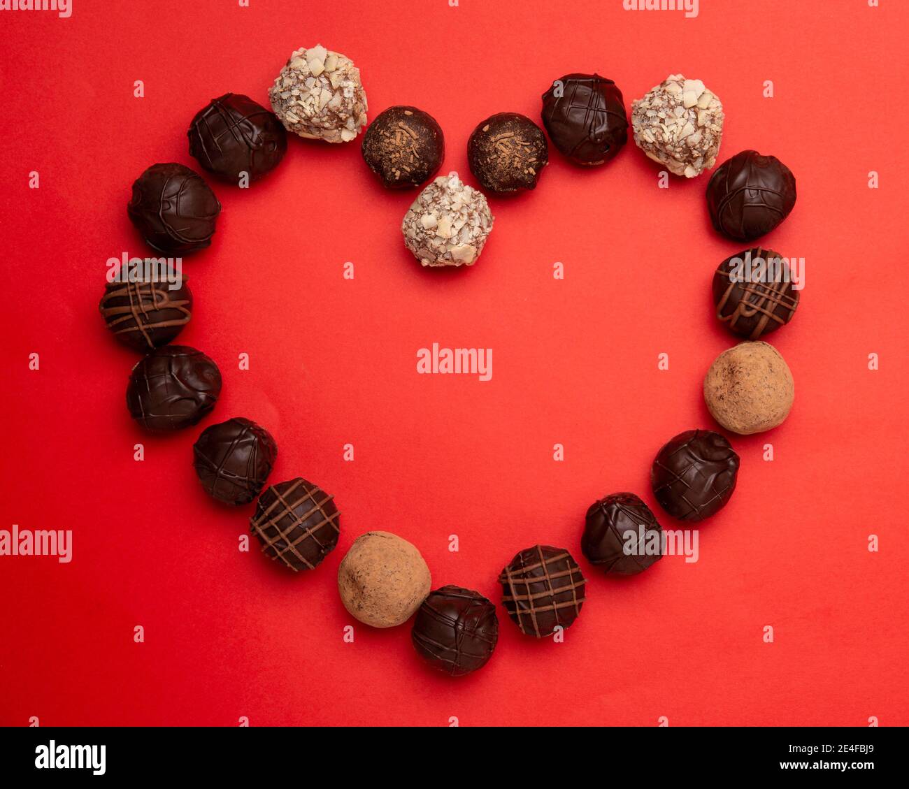 love concept image of heart shape made of chocolate truffles on red ...