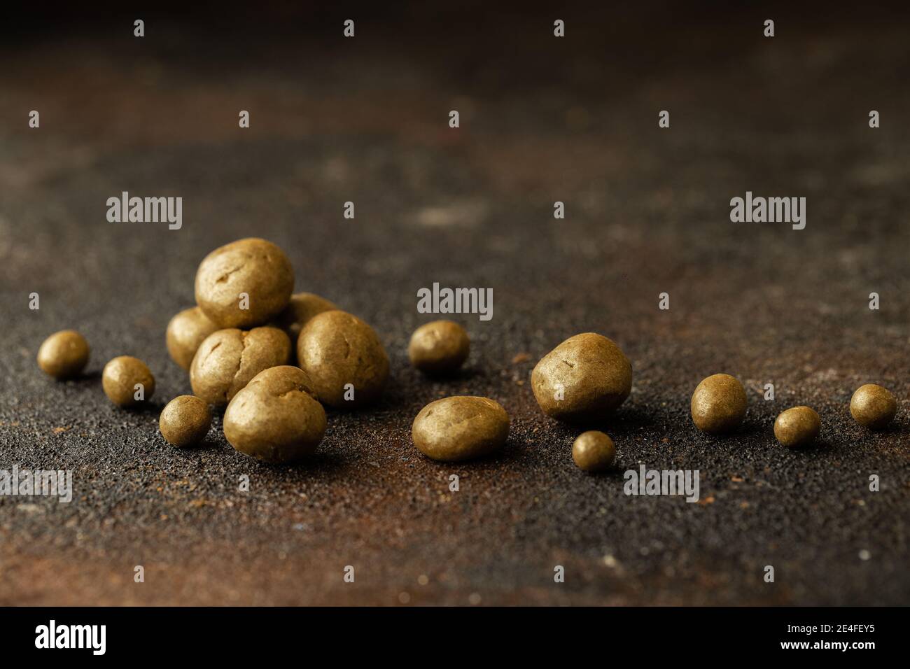 Sweet gold coloured truffles with cinamon, cardamom and clove on a dark ...