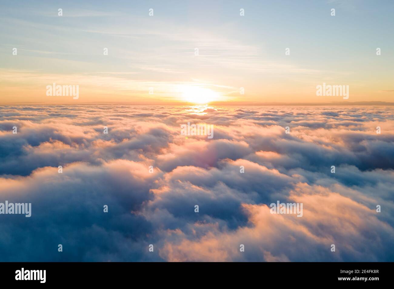 Aerial view of bright yellow sunset over white dense clouds with blue ...