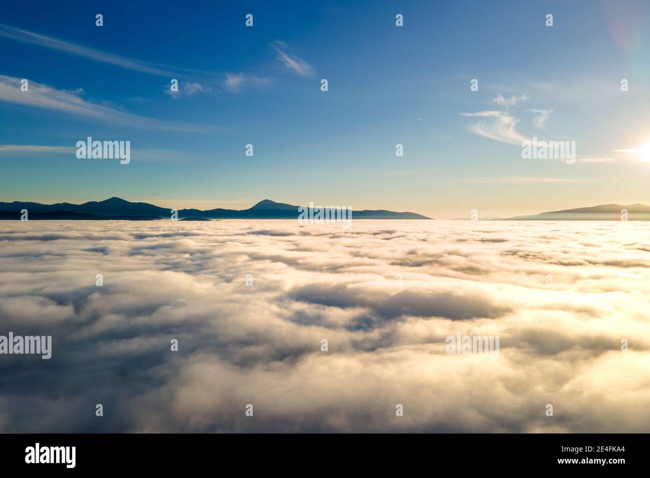 Aerial view of vibrant sunset over white dense clouds with distant dark ...