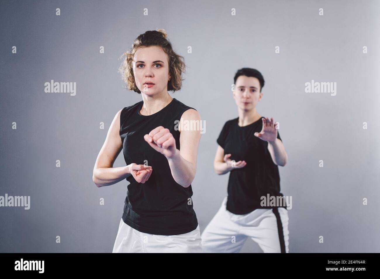 Coach teaches athlete to hit kick. Strong female martial arts athletes ...