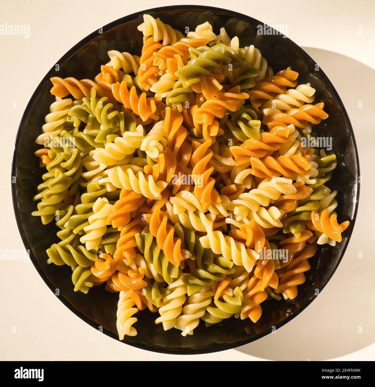 a black plate of fresh italian boiled pasta fusilli served on a withe ...