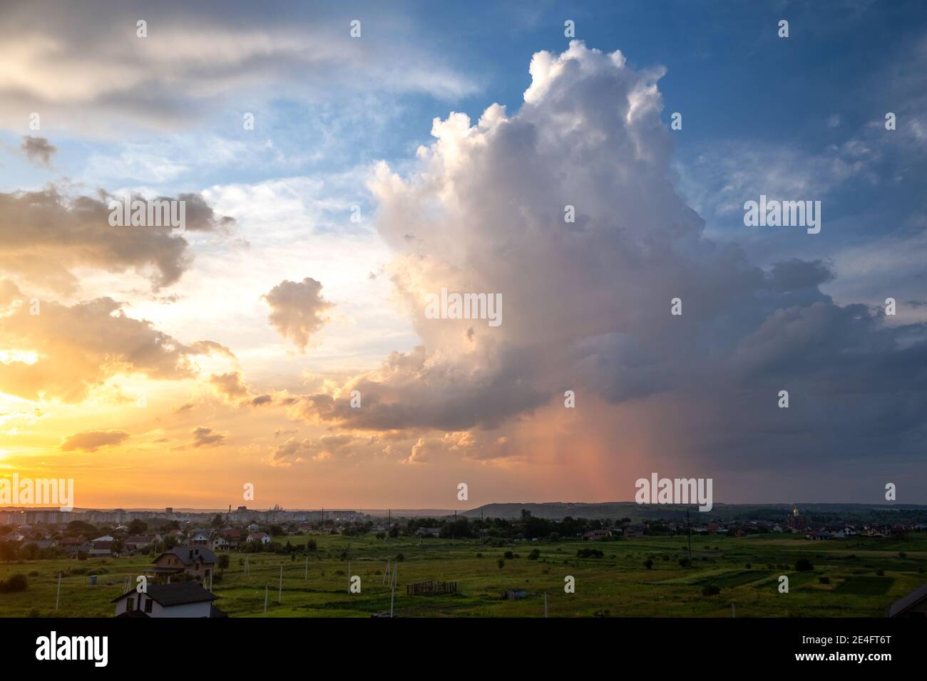 Dramatic sunset landscape of rural area with stormy puffy clouds lit by ...