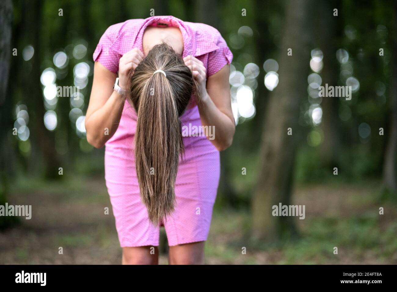 Creepy woman with long hair standing bent down in moody dark forest ...
