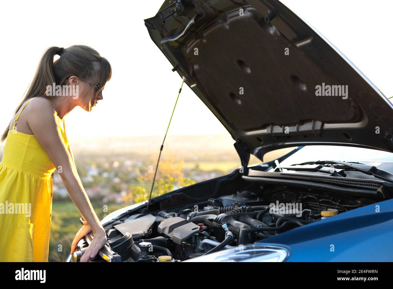 Young woman driver standing near her car with popped hood having engine ...