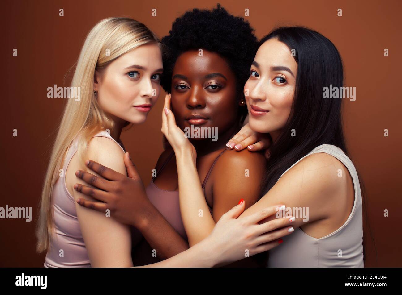 young pretty asian, caucasian, afro woman posing cheerful together on brown background ...