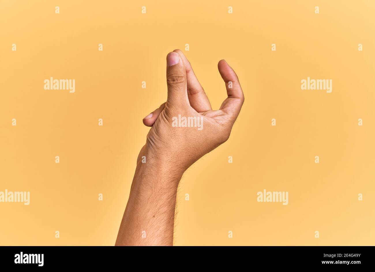 Arm and hand of caucasian man over yellow isolated background snapping ...