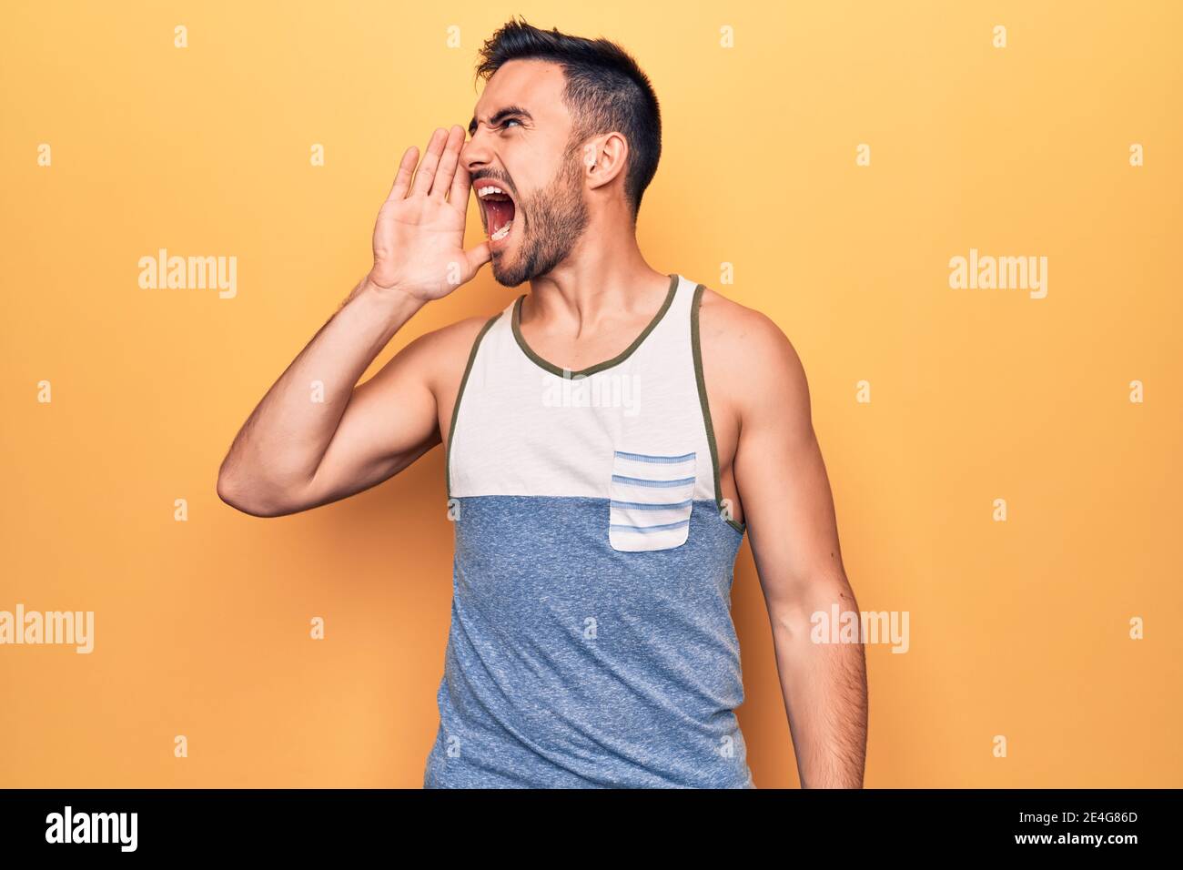Young handsome man with beard wearing sleeveless t-shirt standing over ...