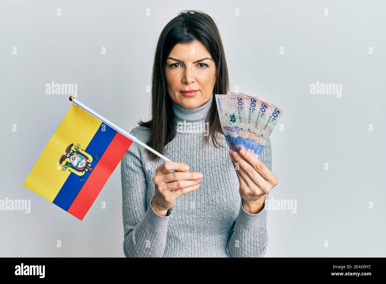 Young hispanic woman holding colombia flag and colombian pesos ...