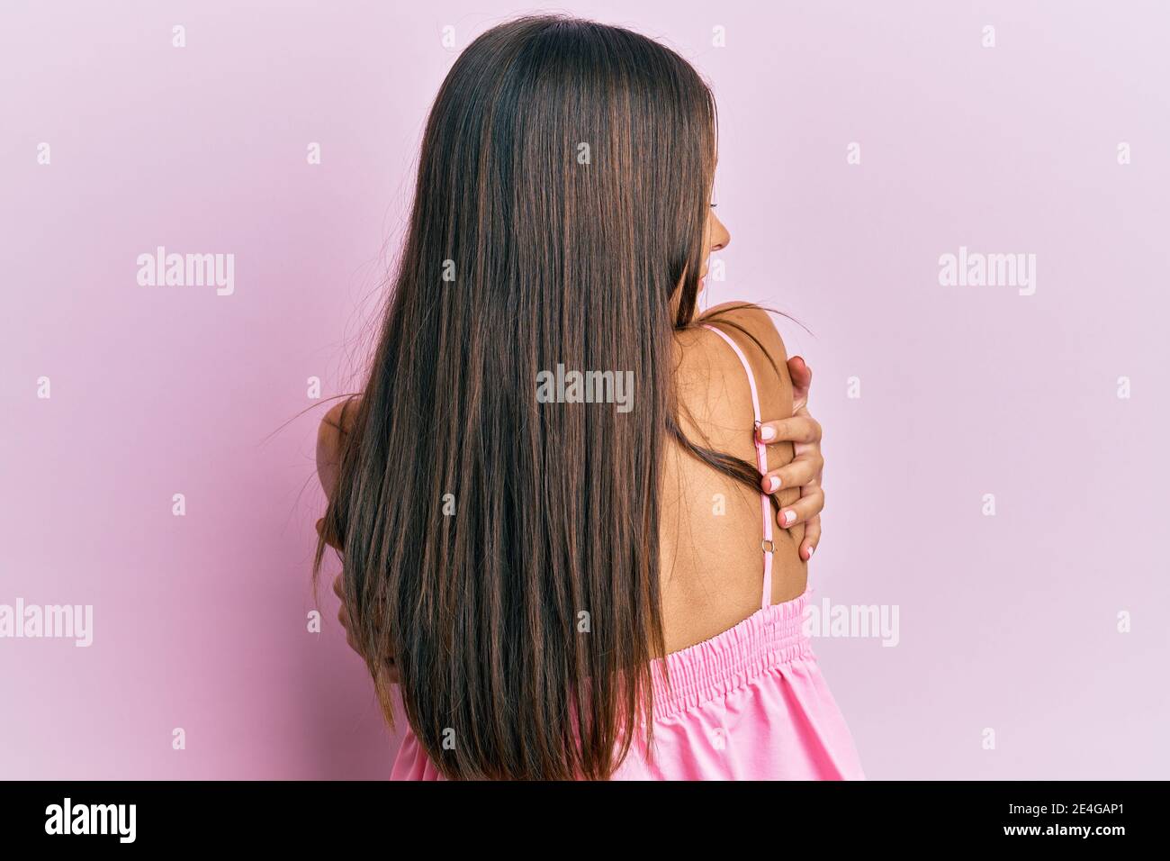 Young hispanic woman wearing casual style with sleeveless shirt hugging oneself happy and ...