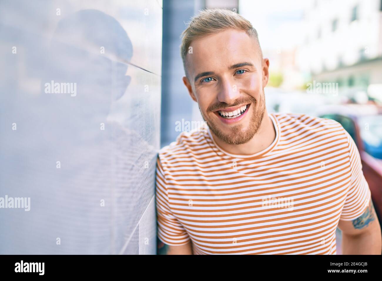 Young irish man smiling happy leaning on the wall at street of city ...