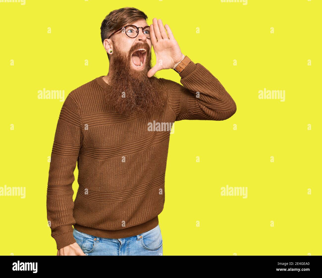 Young irish redhead man wearing casual clothes and glasses shouting and ...