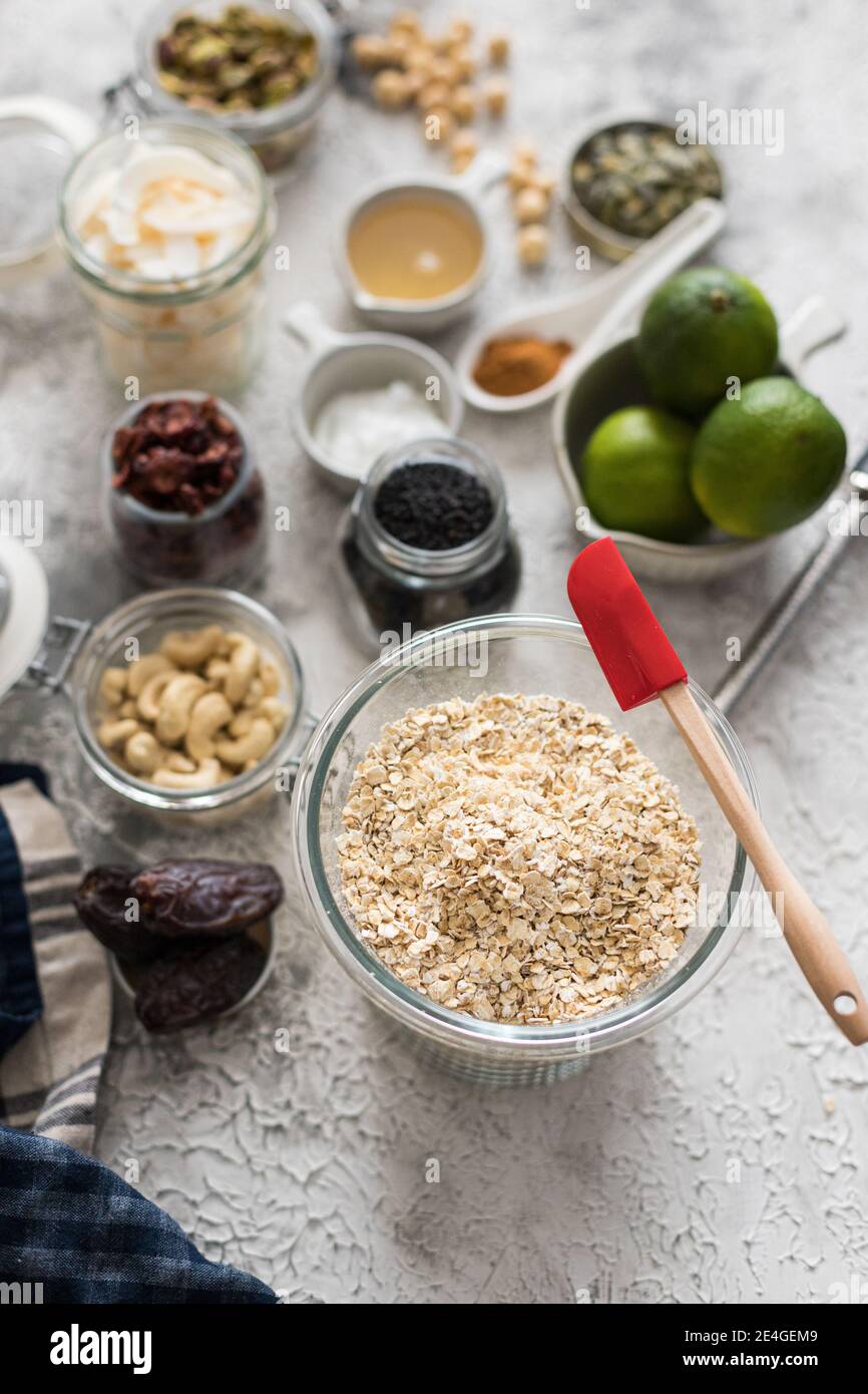 Granola ingredients over a rustic table. A red spatula is over the main ...